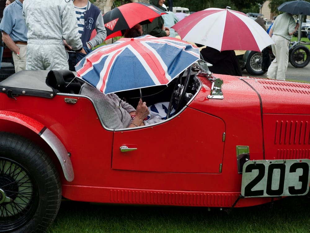Keeping Dry Under Union Jack Umbrella In Vintage Car Art Print by Flo ...